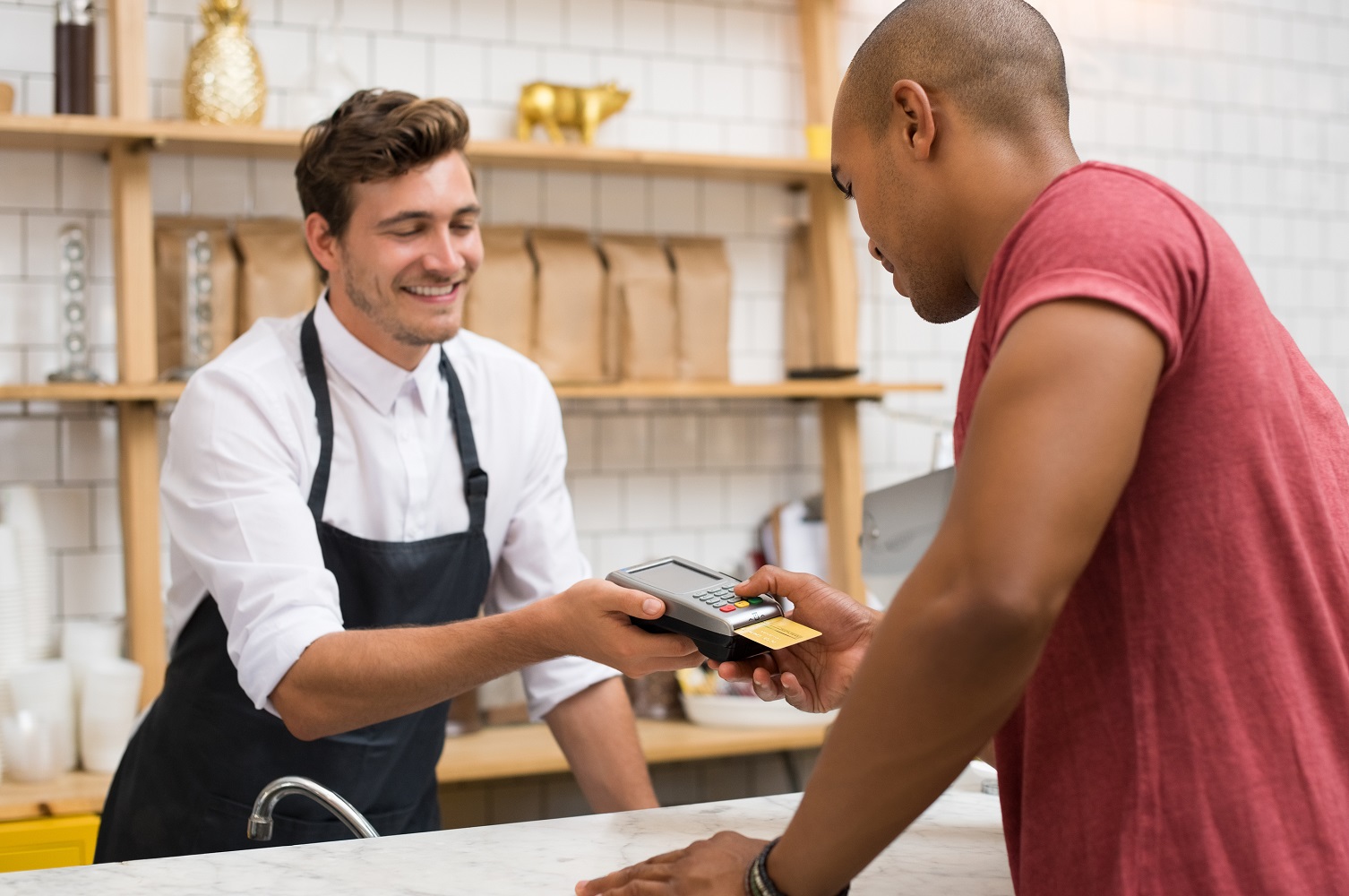 Waiter holding credit card swipe machine while customer typing c ...